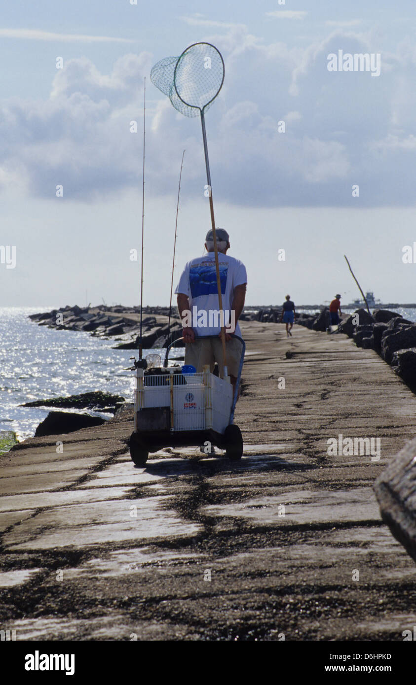 Fishing walking on the rocks with his fishing cart on the jetties at ...
