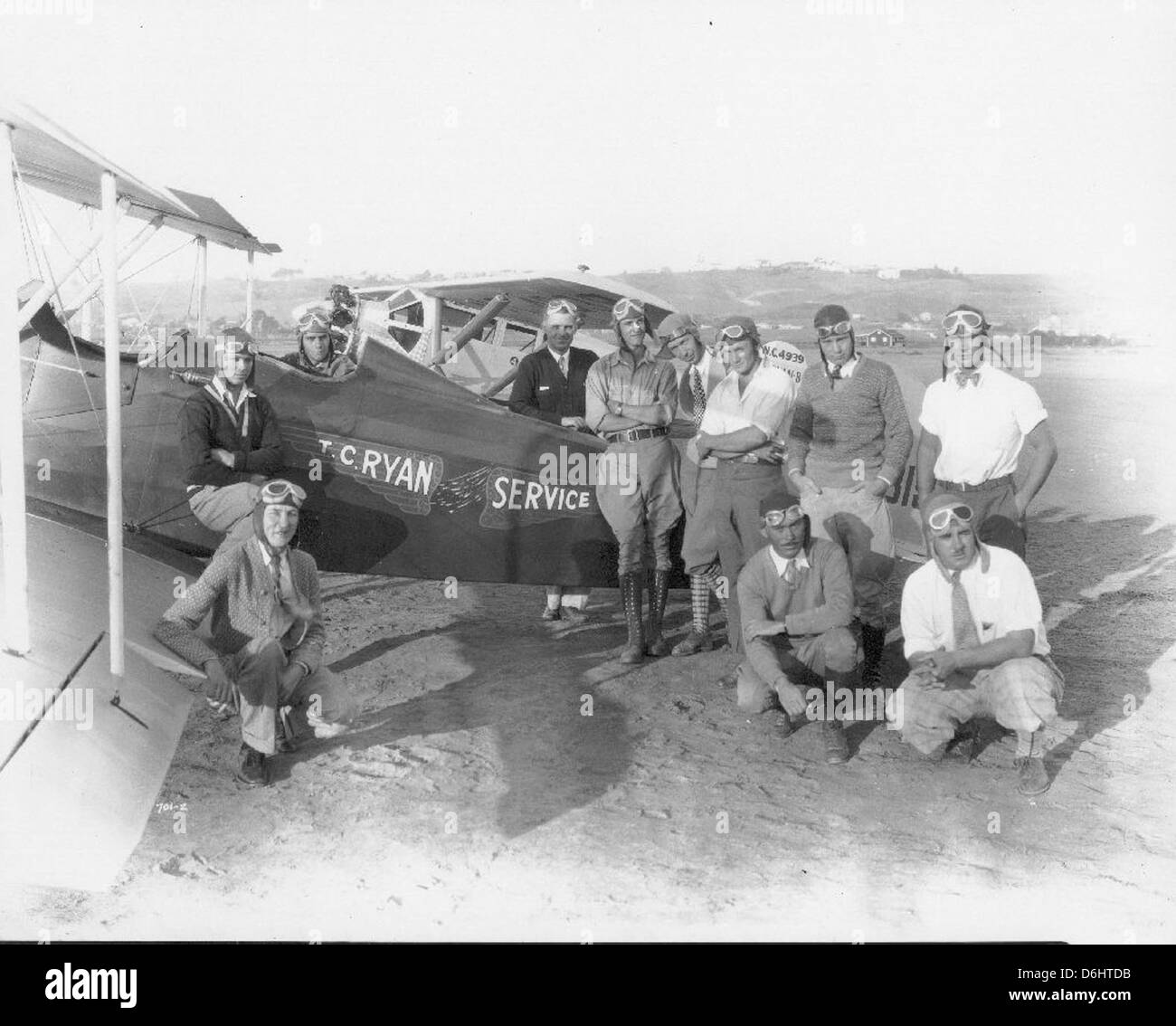This image shows 11 pilots standing next to a Ryan Flying Service plane ...