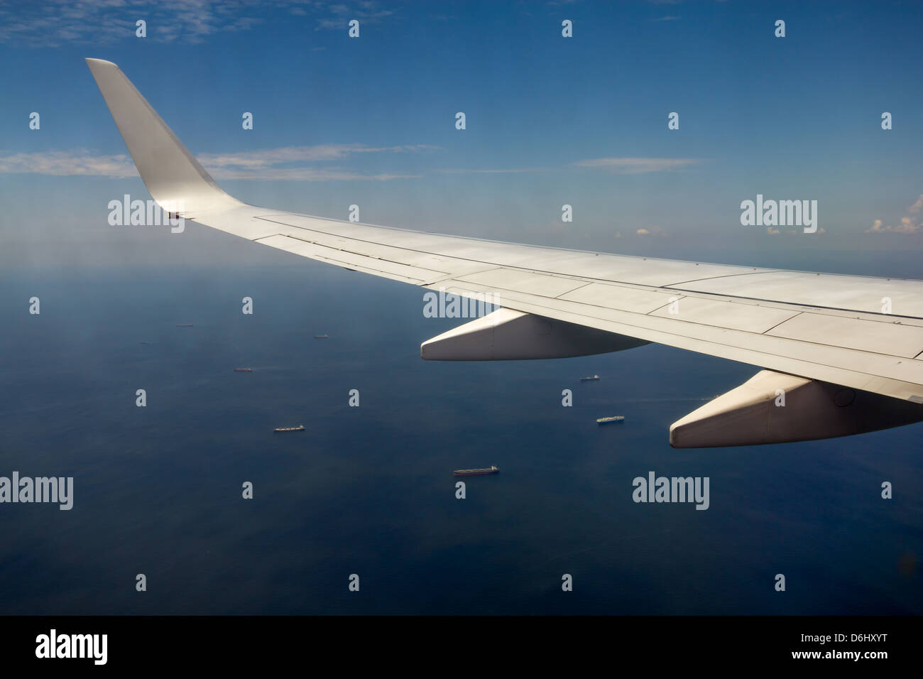 Airplane wing flying over coal ships awaiting loading Stock Photo - Alamy