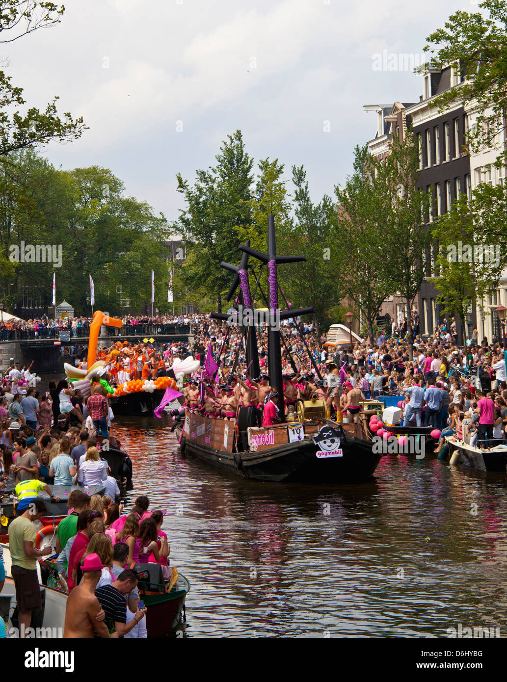 The Gay Pride Parade down a crowded canal lined with people and boats ...