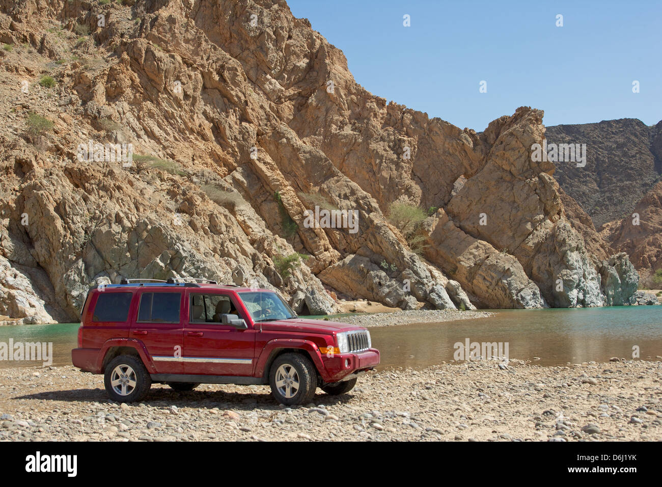 A 4x4 vehicle pauses by a small lake in a wadi in Oman Stock Photo - Alamy