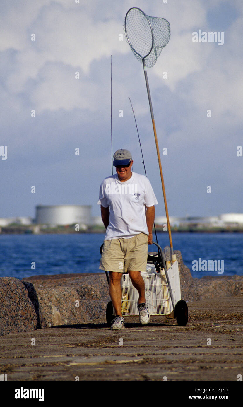 Fishing walking on the rocks with his fishing cart on the jetties at ...