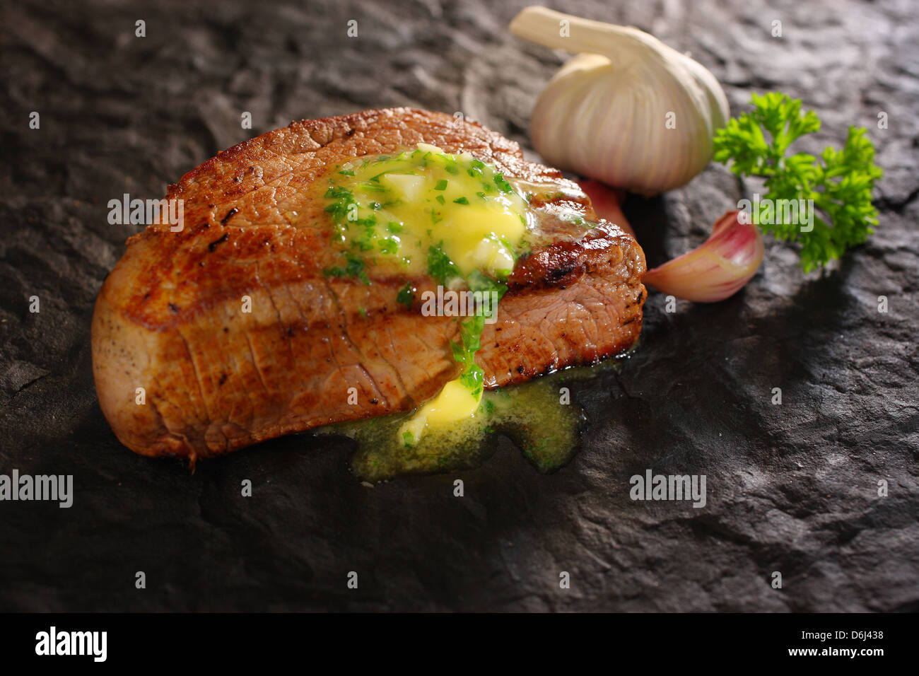 Fillet of steak with melted garlic butter on black slate Stock Photo ...