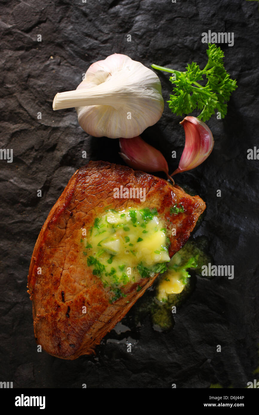 Fillet of steak with melted garlic butter on a black slate Stock Photo ...