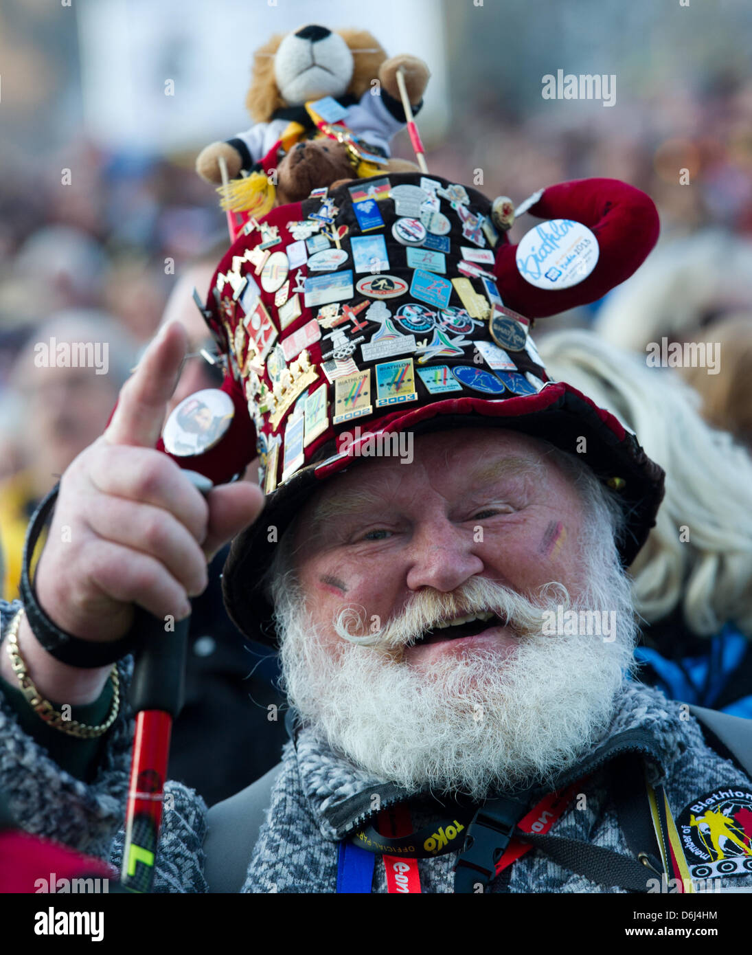 A biathlete fan with various pins on his hat stands during the mixed ...