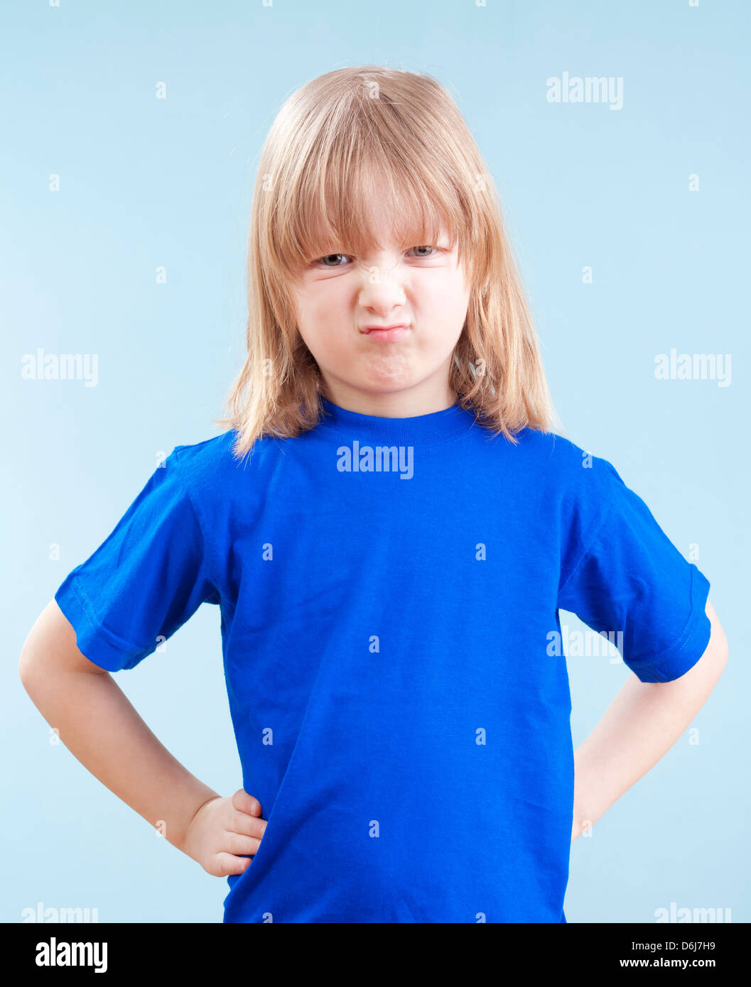 angry boy with long blond hair standing looking - isolated on blue ...