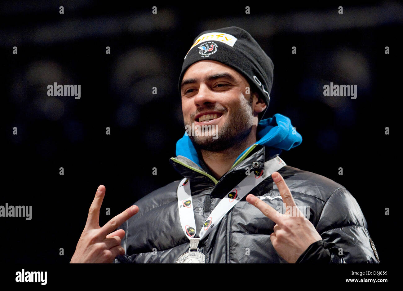 French biathlete Simon Fourcade smiles and gestures a victory sign ...