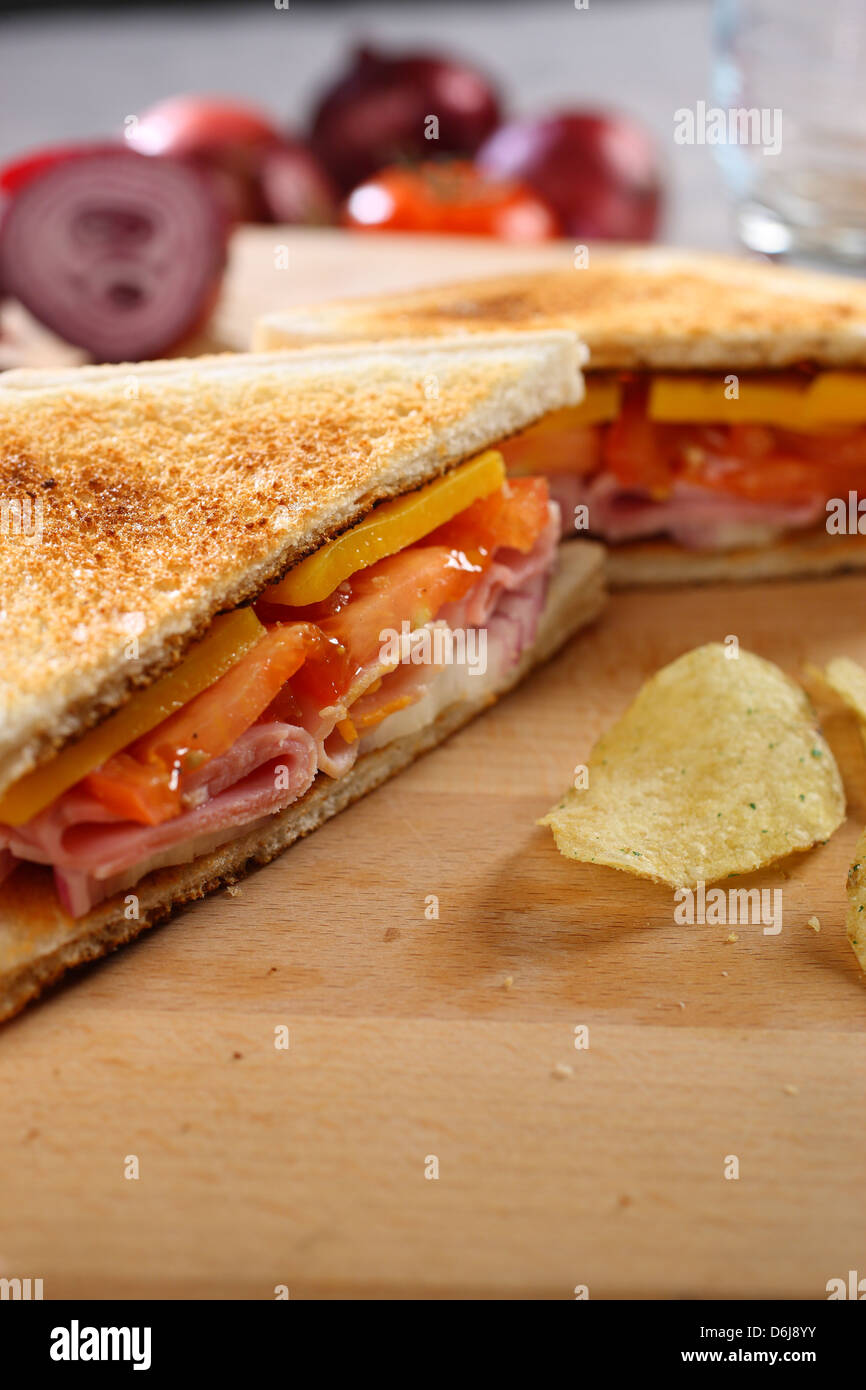 Closeup of toasted ham cheese tomato sandwich on a wooden breadboard ...