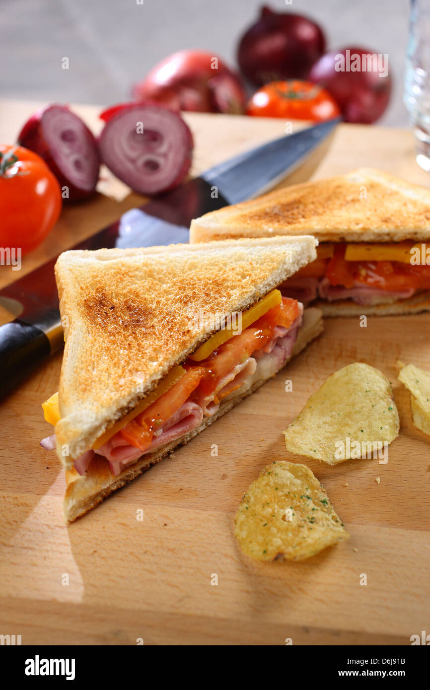 toasted ham cheese tomato sandwich with crisps on a wooden breadboard ...