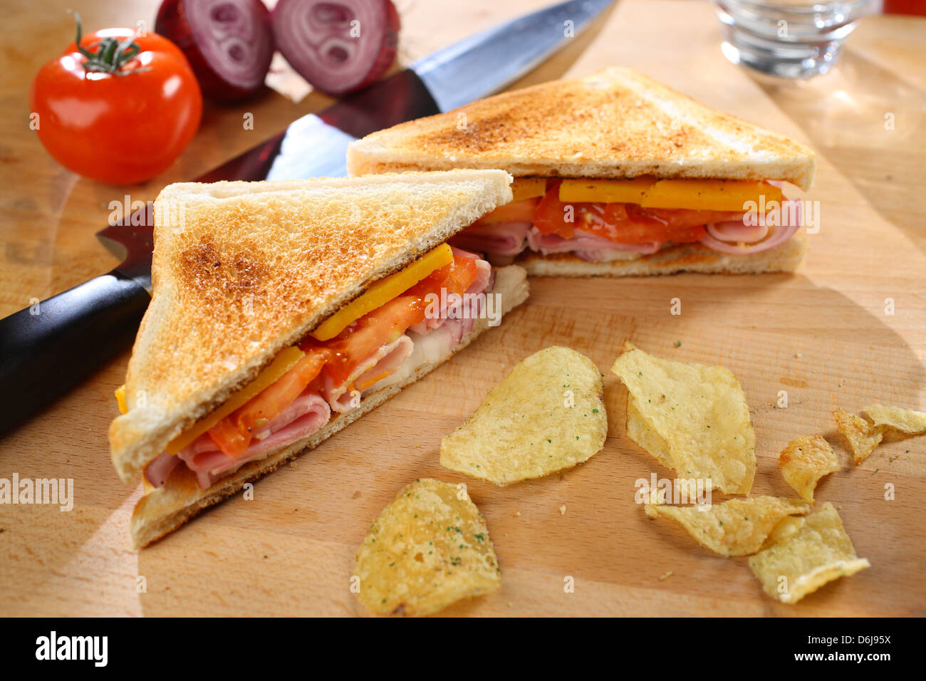toasted ham cheese and tomato sandwich with crisps on a wooden ...