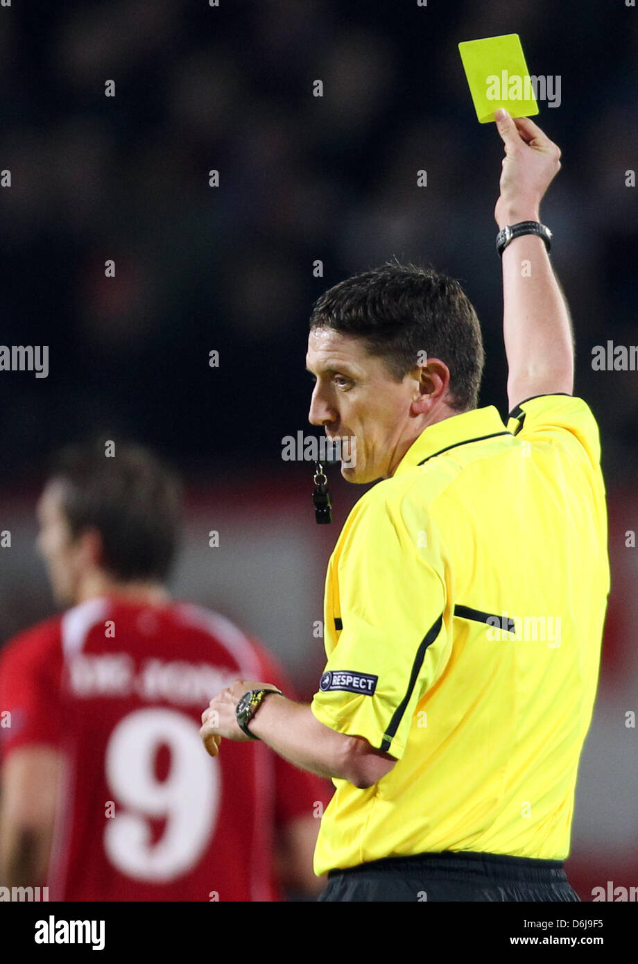 Referee Craig Thomson (R) shows a yellow card during the Europa League ...