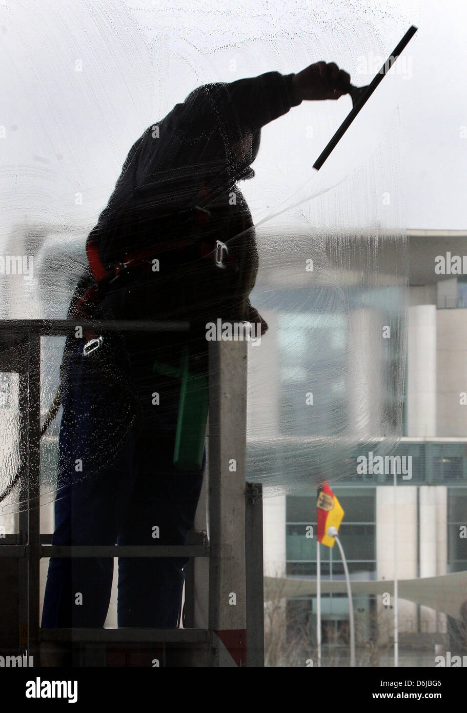 A man cleans a window of the Paul-Loebe-House in front of the ...