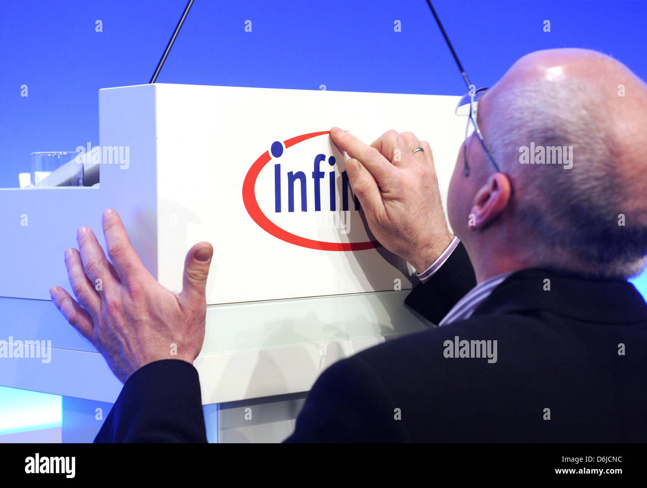 A man sticks the logo of semiconductor manufacturer Infineon onto the ...