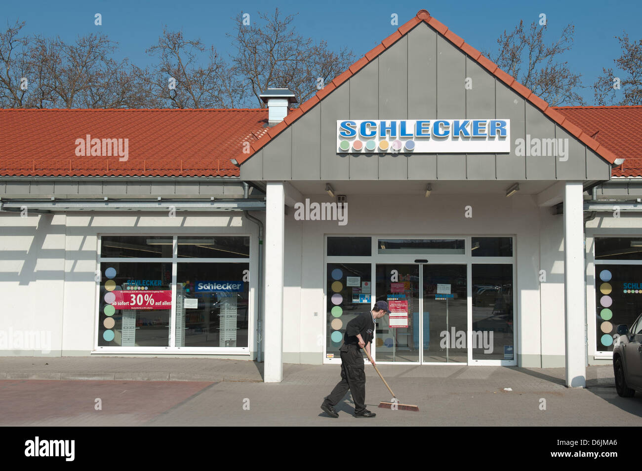 A man sweeps the floor in front of the entrance to a a branch of the ...