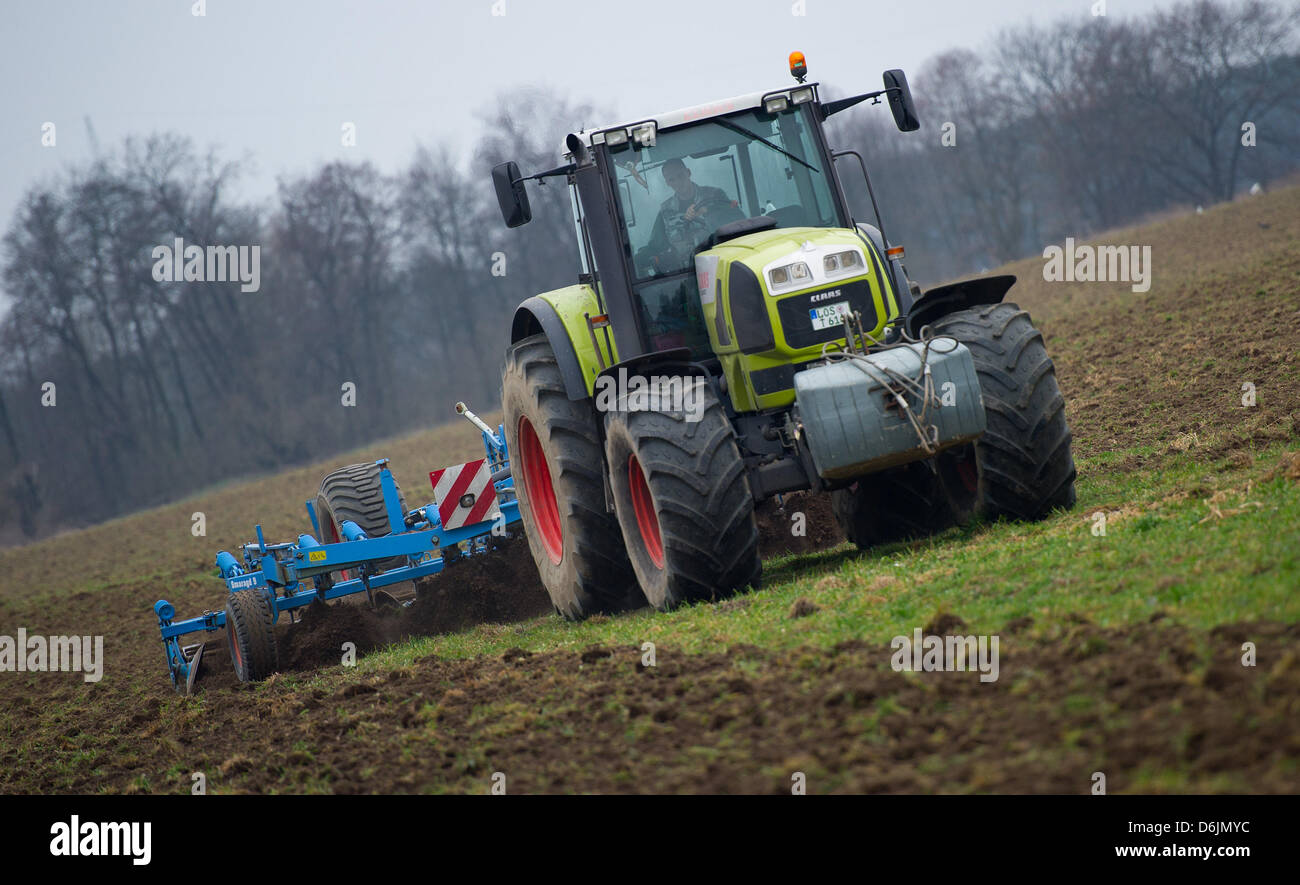 A farmer drives his tractor with an attached harrow across a fieldnear ...