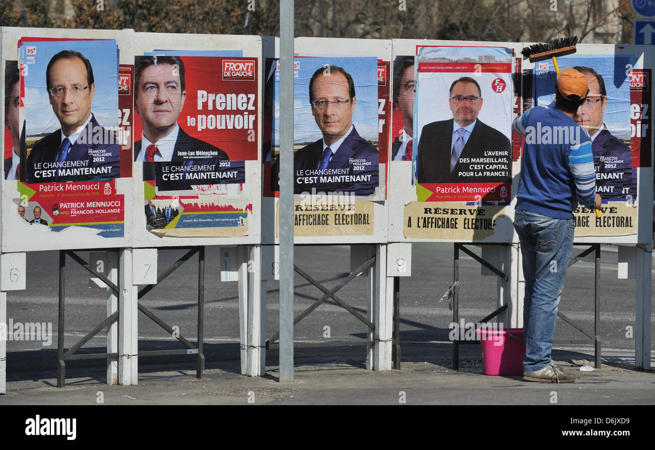A man puts up election posters of candidates for the French ...