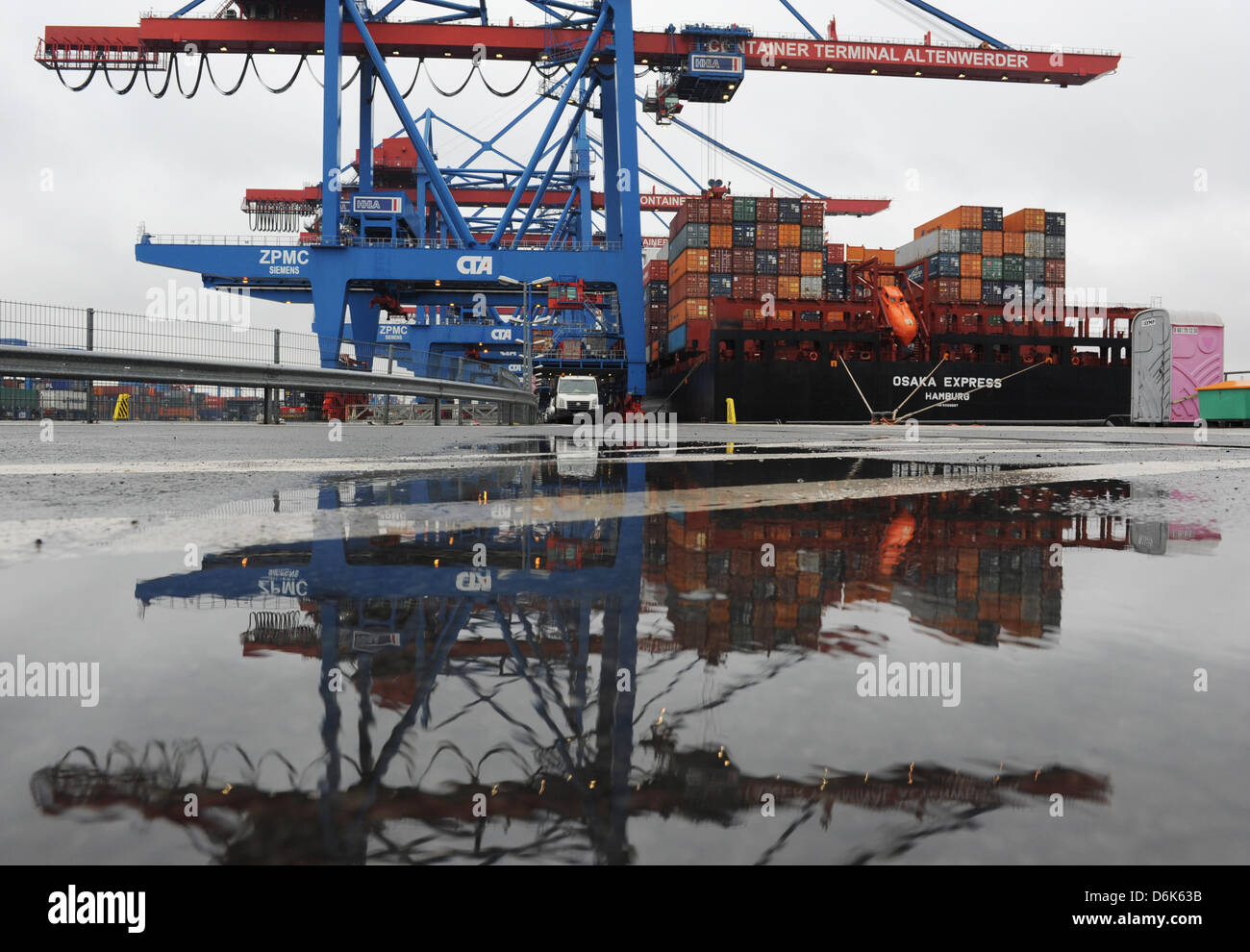 A container ship "Osake Express" in reflected is a pool of rain water ...