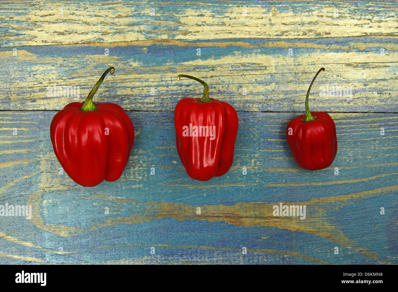 Three chili peppers on old wood background Stock Photo - Alamy