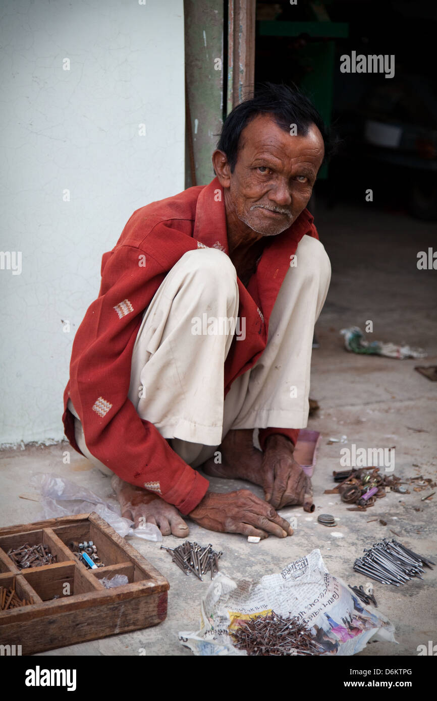 A construction worker sorts nails on a building site in Balasinor ...