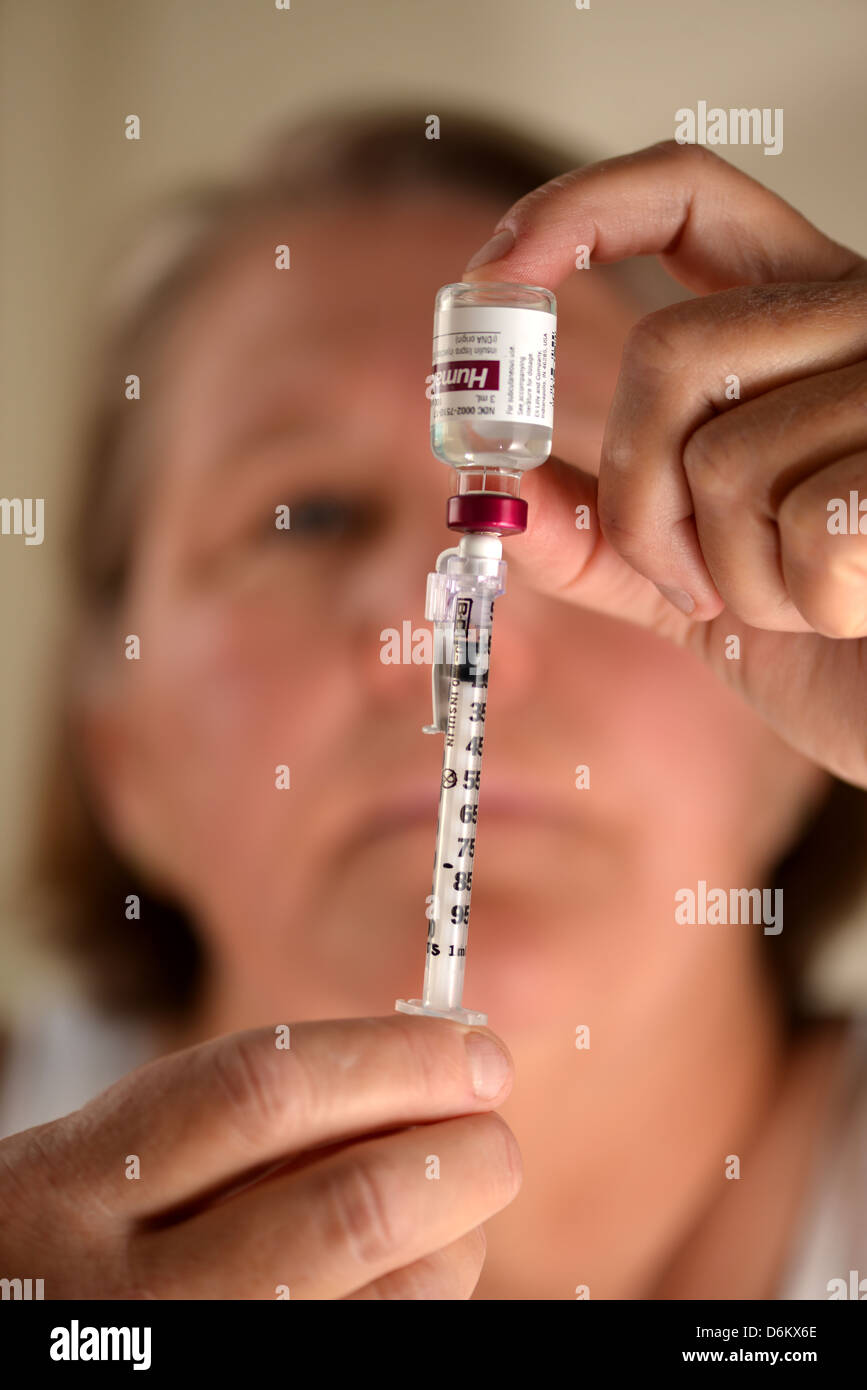 A senior female prepares a syringe with insulin, which is used to treat ...