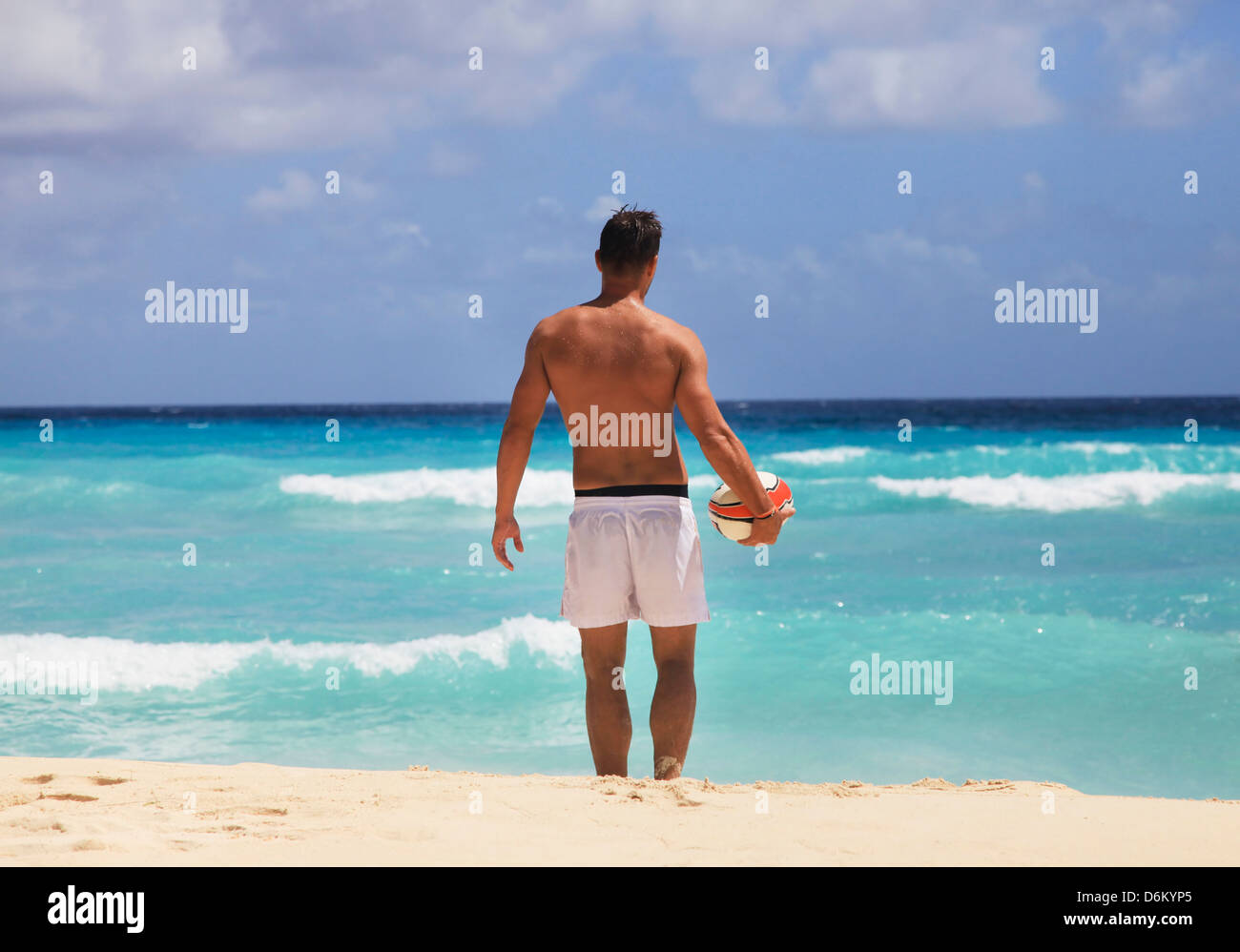 Young man with ball on beach Stock Photo - Alamy