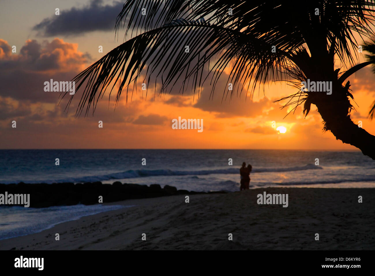 Romantic couple at beach with sunset in the background at Barbados ...