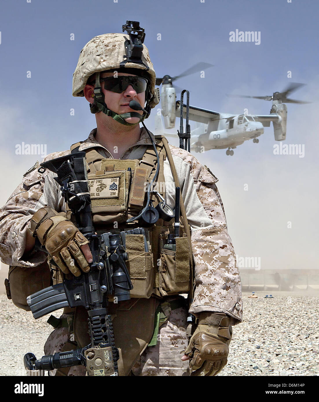 A US Marine provides security while an MV-22 Osprey transport aircraft ...
