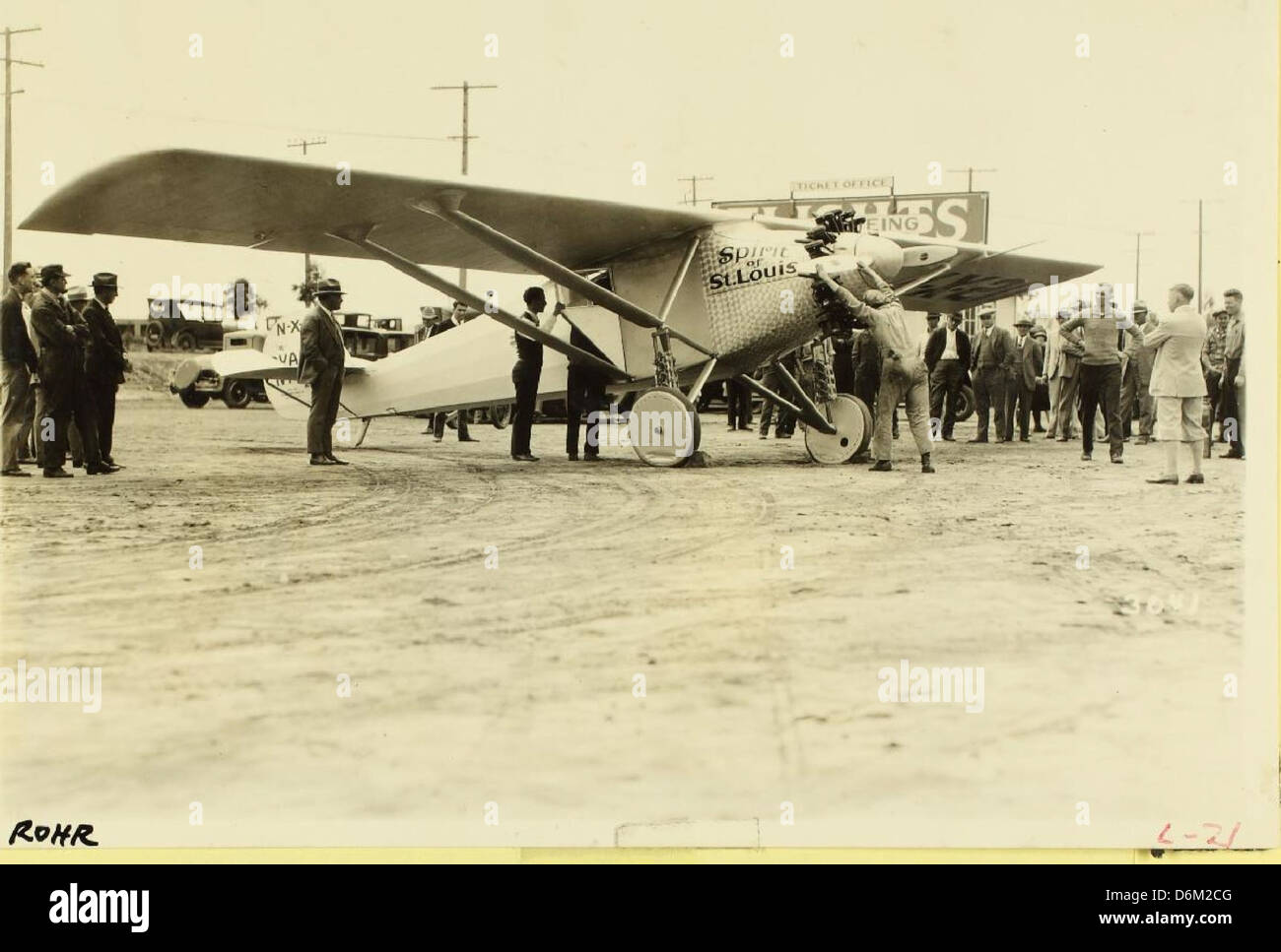 The image shows Charles Lindbergh standing next to an aircraft, likely ...