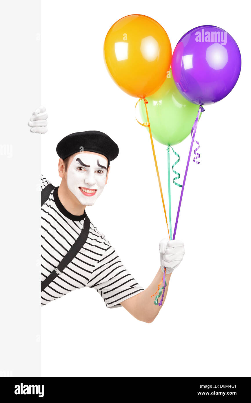 Mime artist holding a bunch of balloons and peeking from a white panel ...