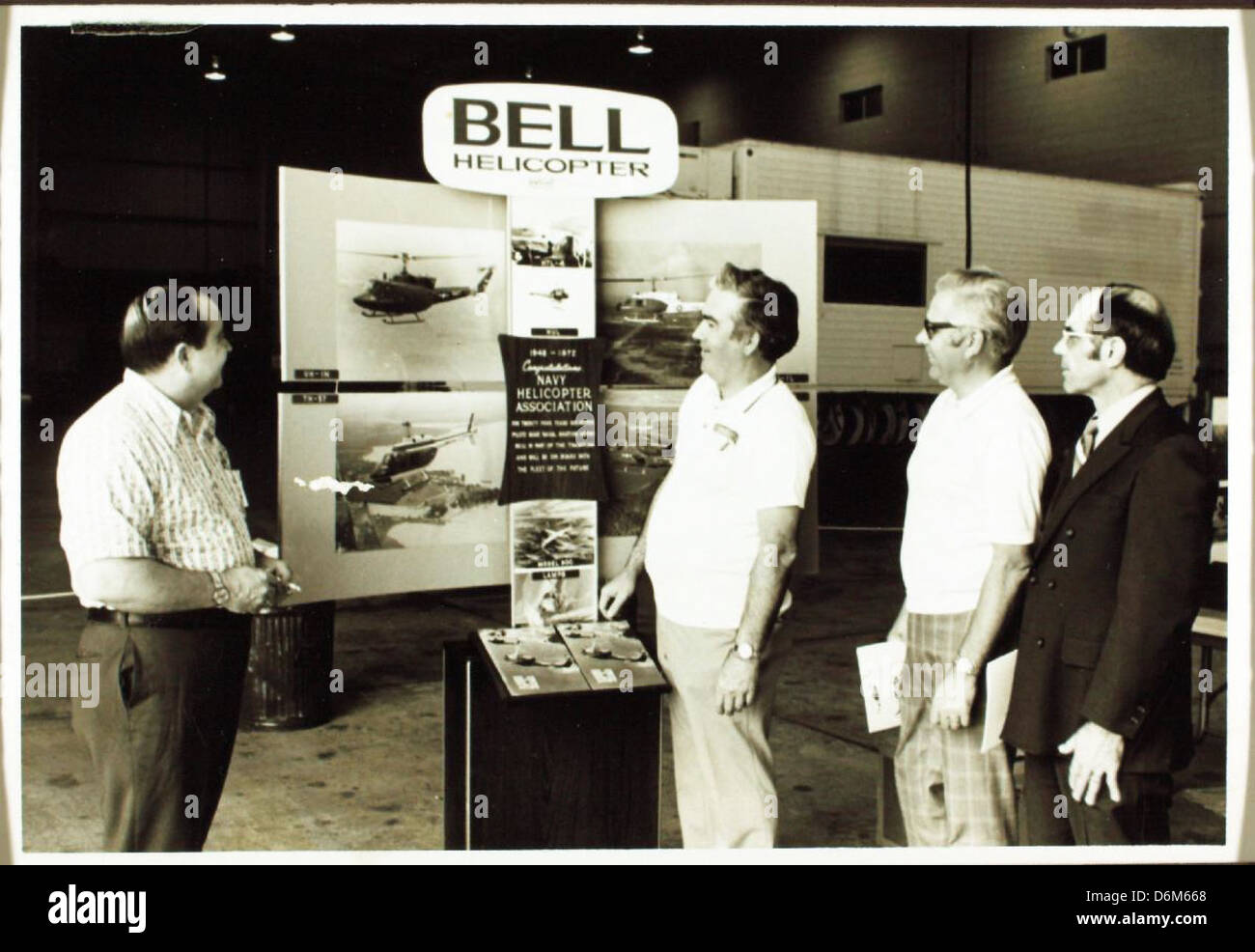 This image captures men observing a Bell Helicopter display, reflecting ...