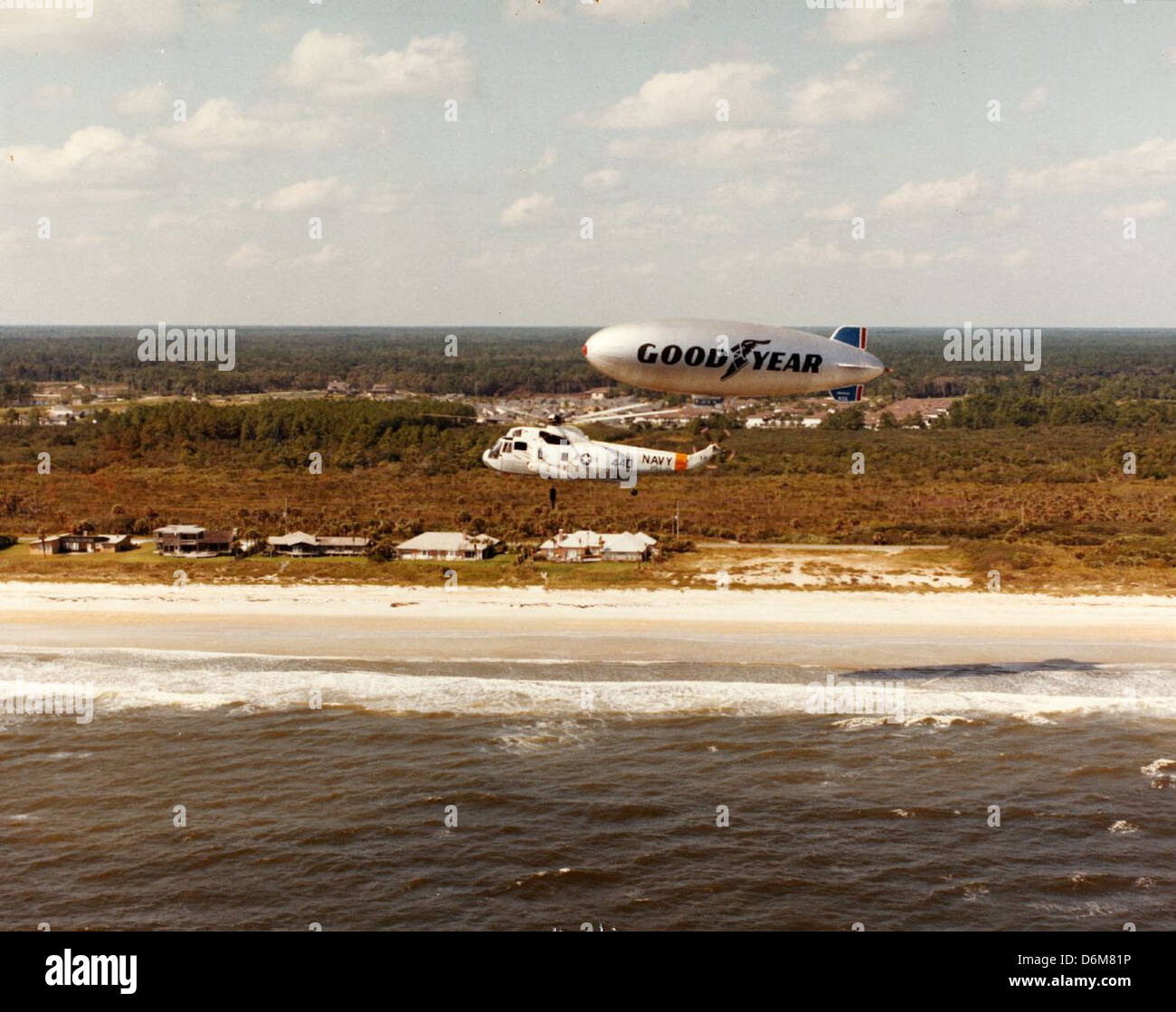 The H-3 helicopter flying above the coast alongside a blimp captures a ...