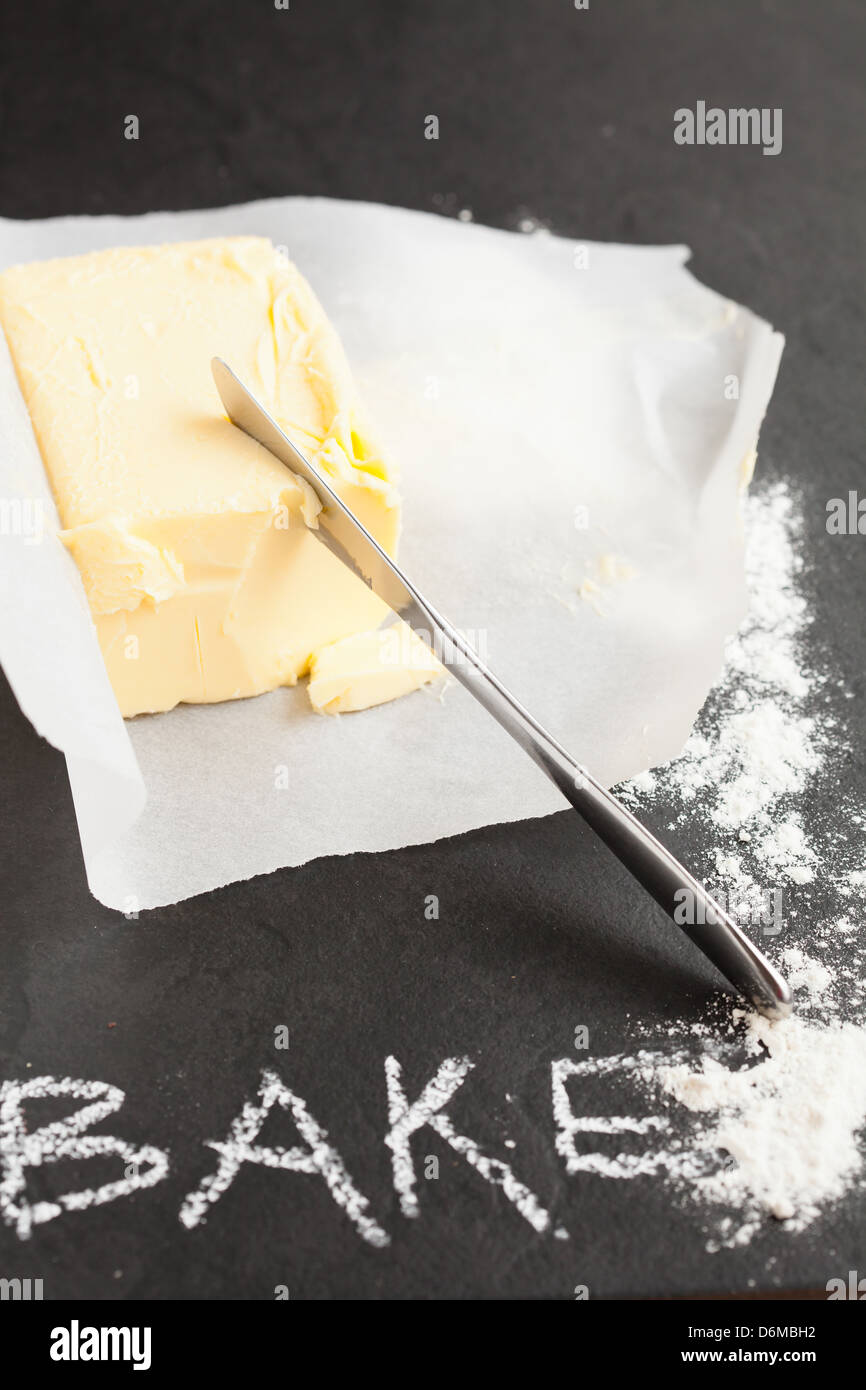 Closeup of block of butter in baking paper and knife with word bake ...