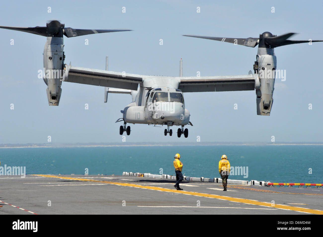 US Navy flight operations sailors direct a MV-22 Osprey aircraft to ...