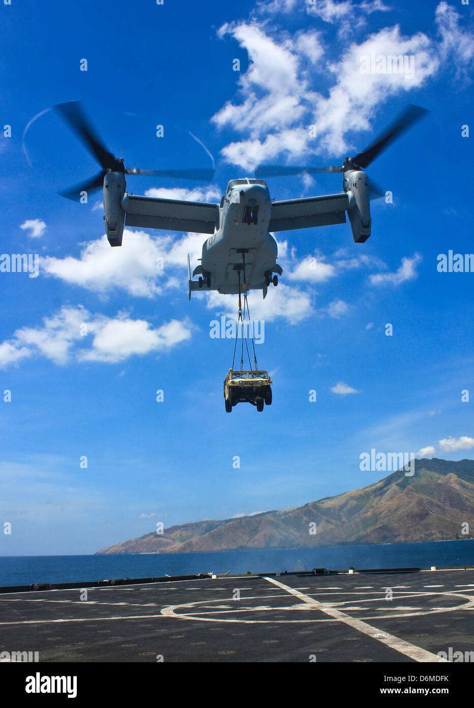 A US Marine Corps MV-22B Osprey lifts a Humvee jeep from the deck of ...