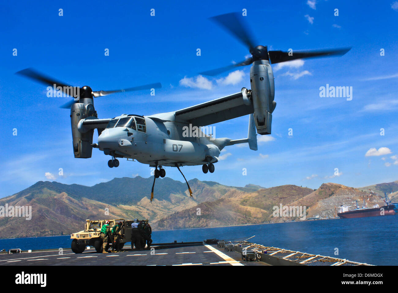 A US Marine Corps MV-22B Osprey lifts a Humvee jeep from the deck of ...