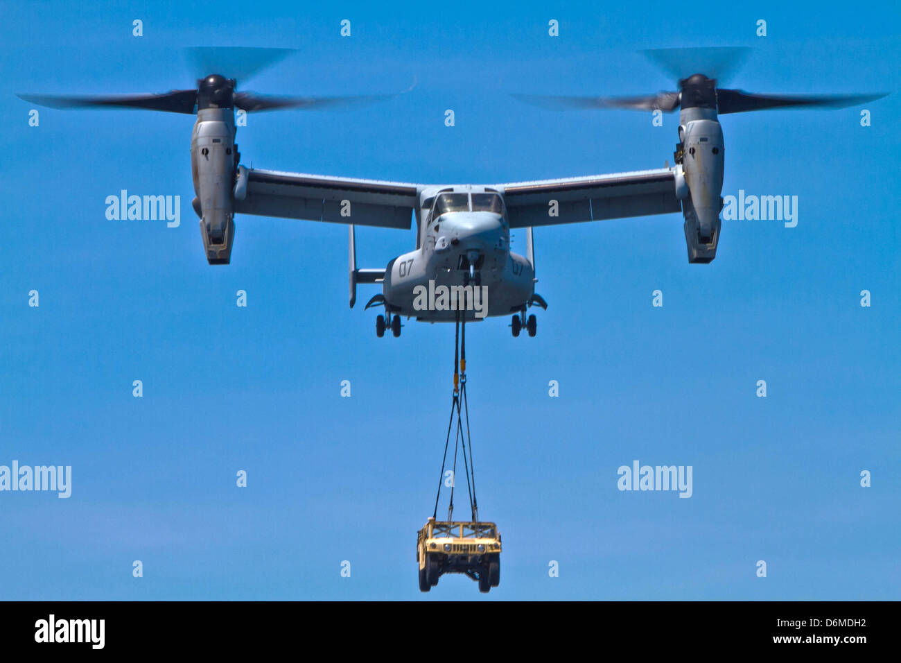 A US Marine Corps MV-22B Osprey lifts a Humvee jeep from the deck of ...