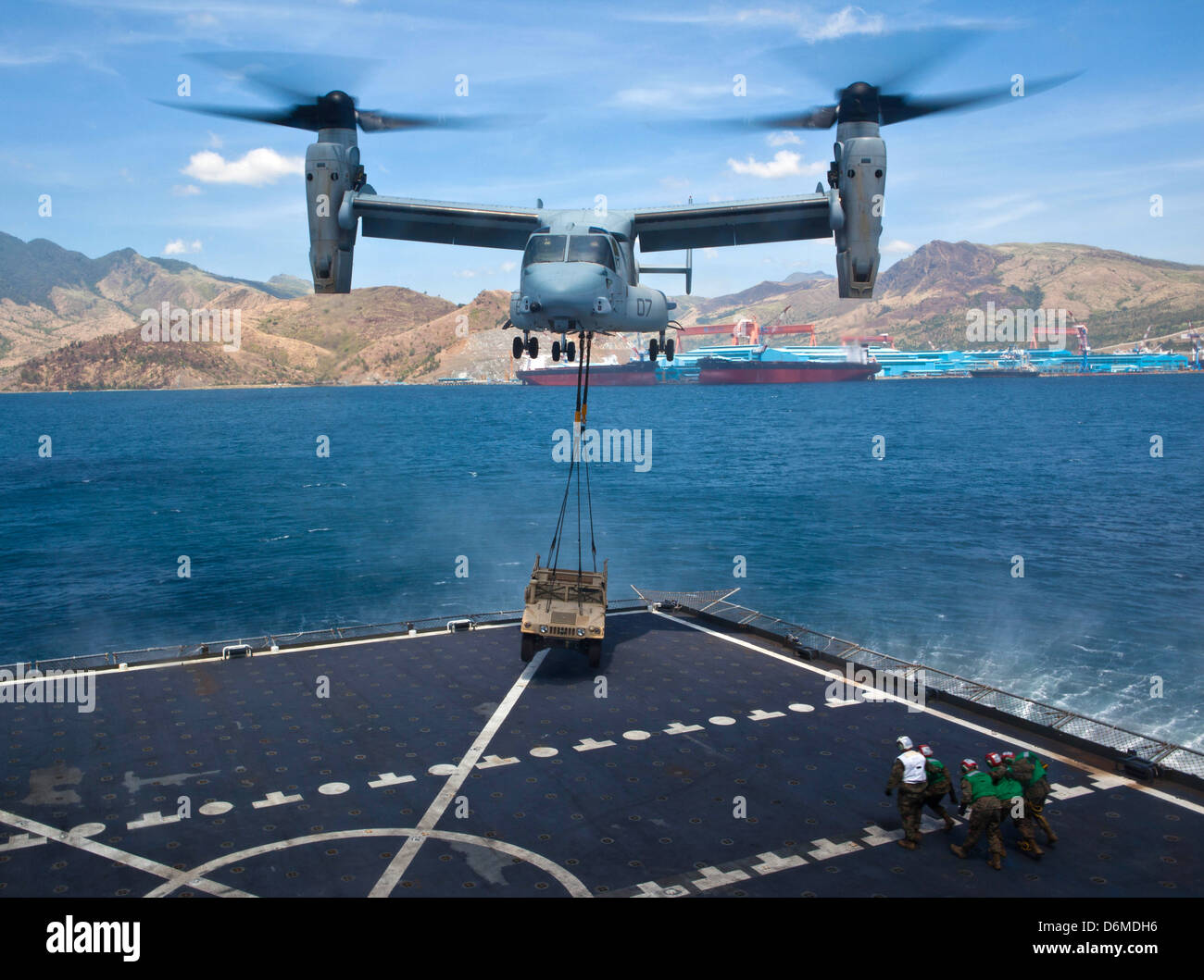 A US Marine Corps MV-22B Osprey lifts a Humvee jeep from the deck of ...