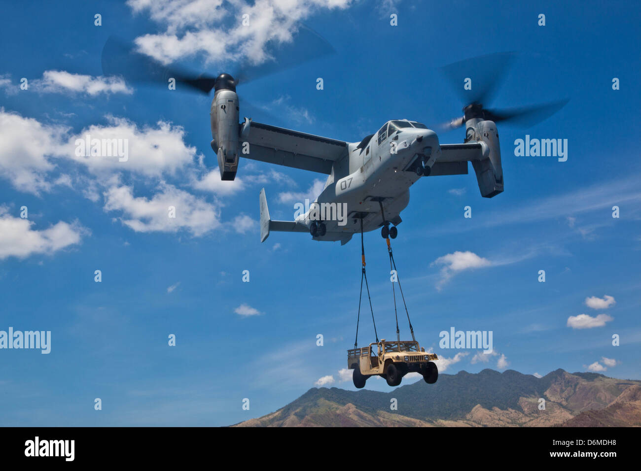 A US Marine Corps MV-22B Osprey lifts a Humvee jeep from the deck of ...