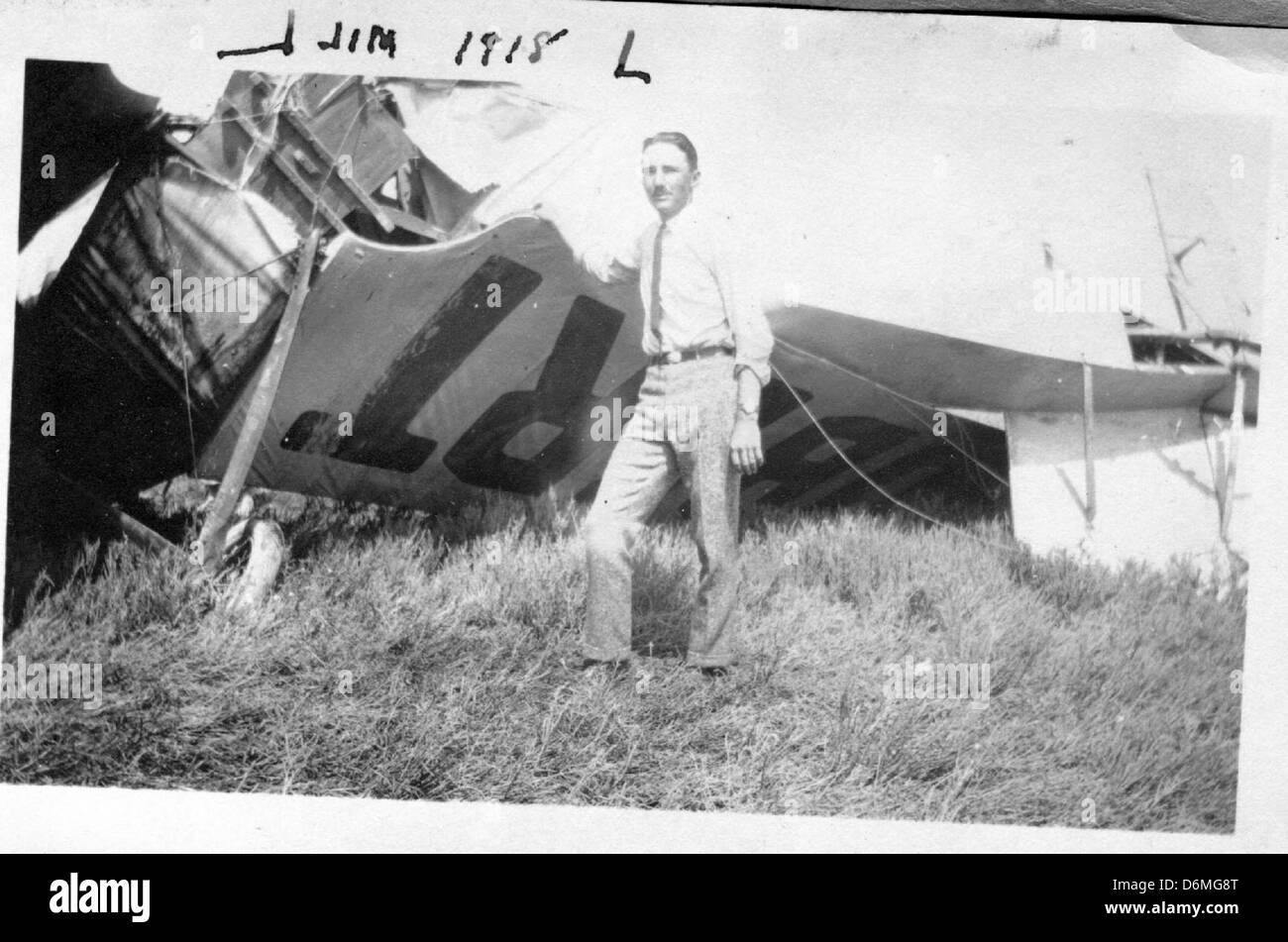 This photograph depicts Jim Hester next to a wrecked aircraft. The ...