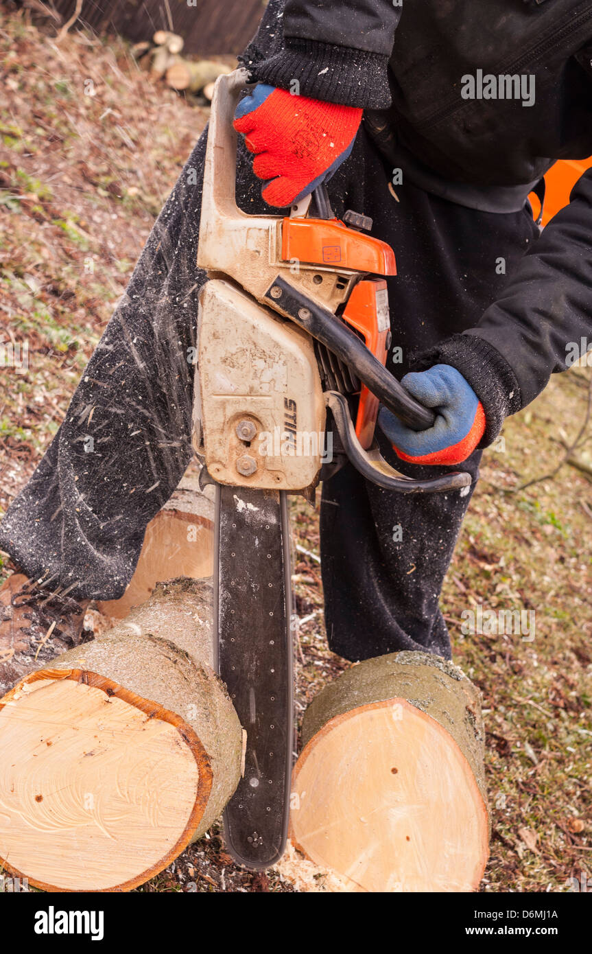 A man cutting logs with a chainsaw showing movement in the Uk Stock ...