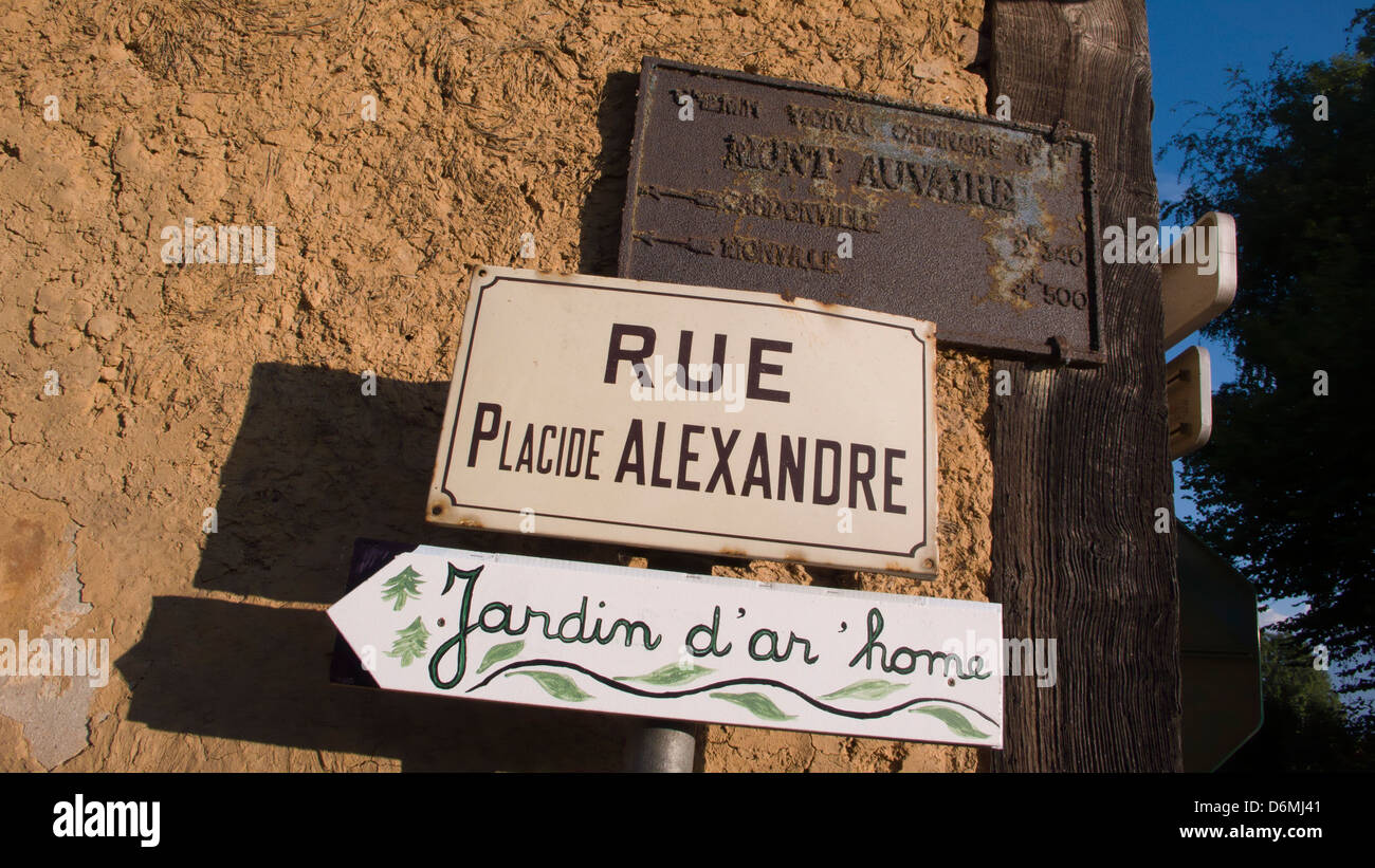 Old and new street signs,against ancient mud wall, Normandy, France ...