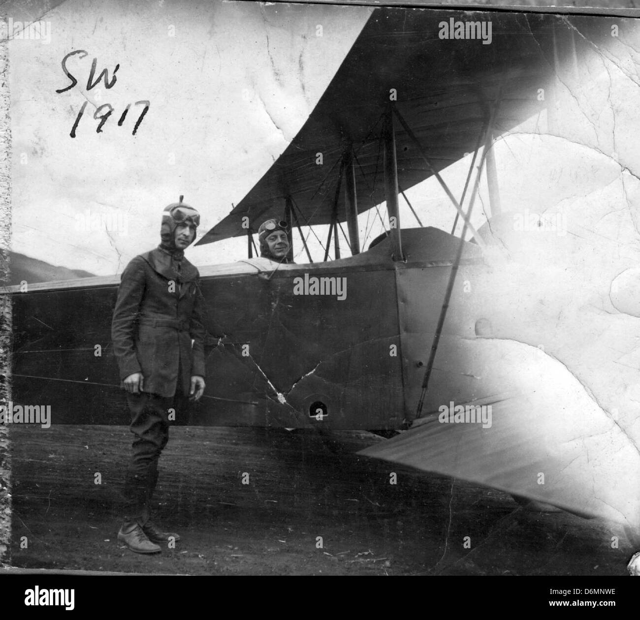 This 1917 photograph captures a man standing next to planes, offering a ...