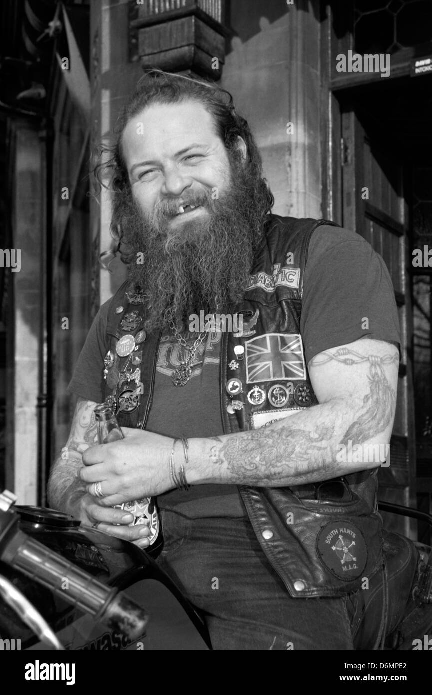 biker smiling outside of pub holding beer bottle Stock Photo - Alamy