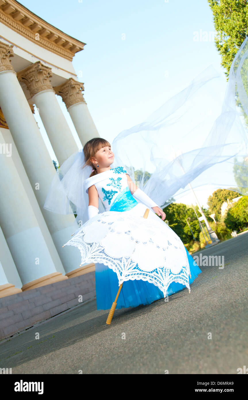 Little bride. A girl in a lush white and blue wedding dress and veil ...