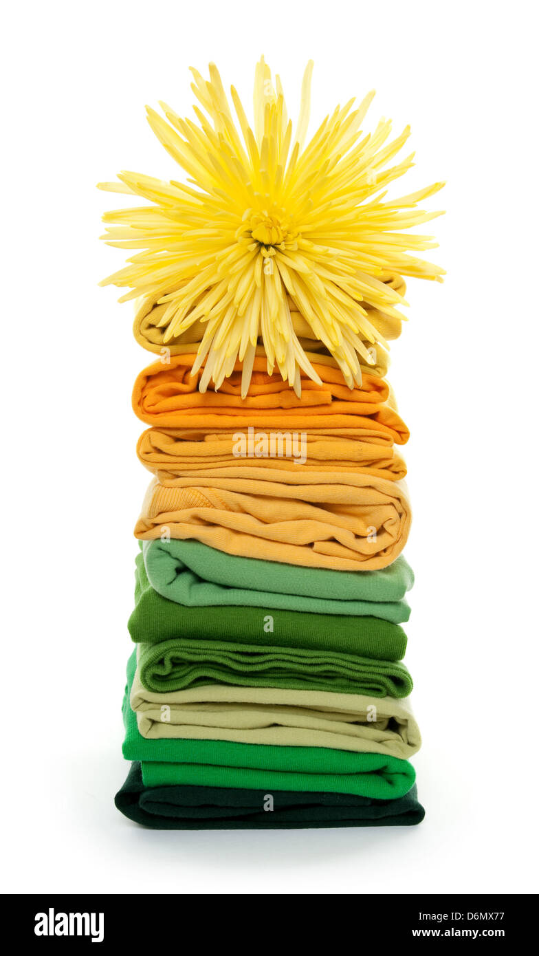 Joyful spring laundry. Flower on top of green and yellow folded clothes ...