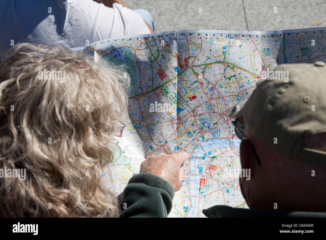 Man reading a map in Trafalgar Square London, pointing to a destination ...