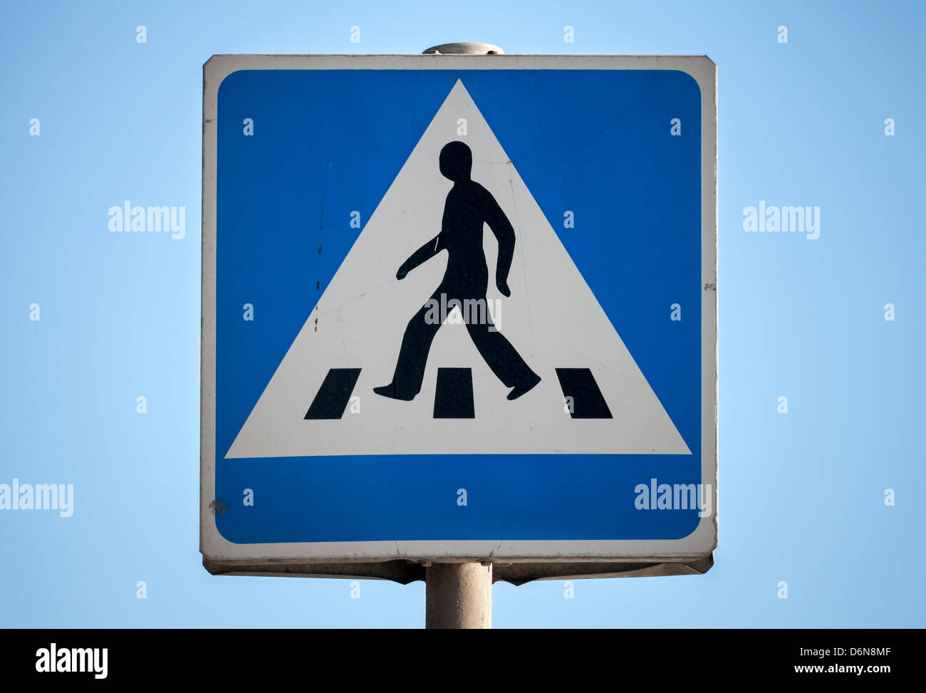 Close up photo of blue square pedestrian crossing sign above blue sky ...