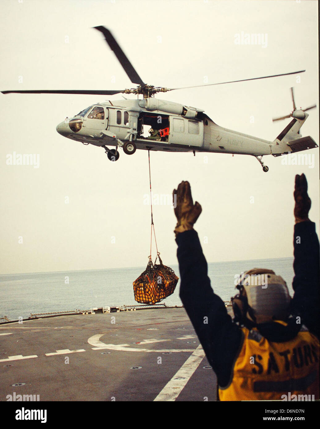 This photograph shows a CH-60 helicopter on a flight deck with its ...