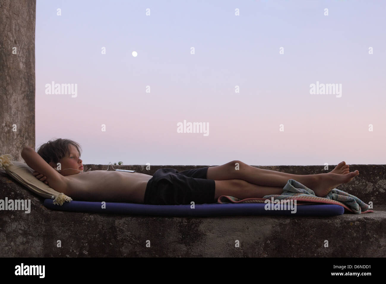 Alicudi, Italy, boy lies on his mattress at night and hears music from ...