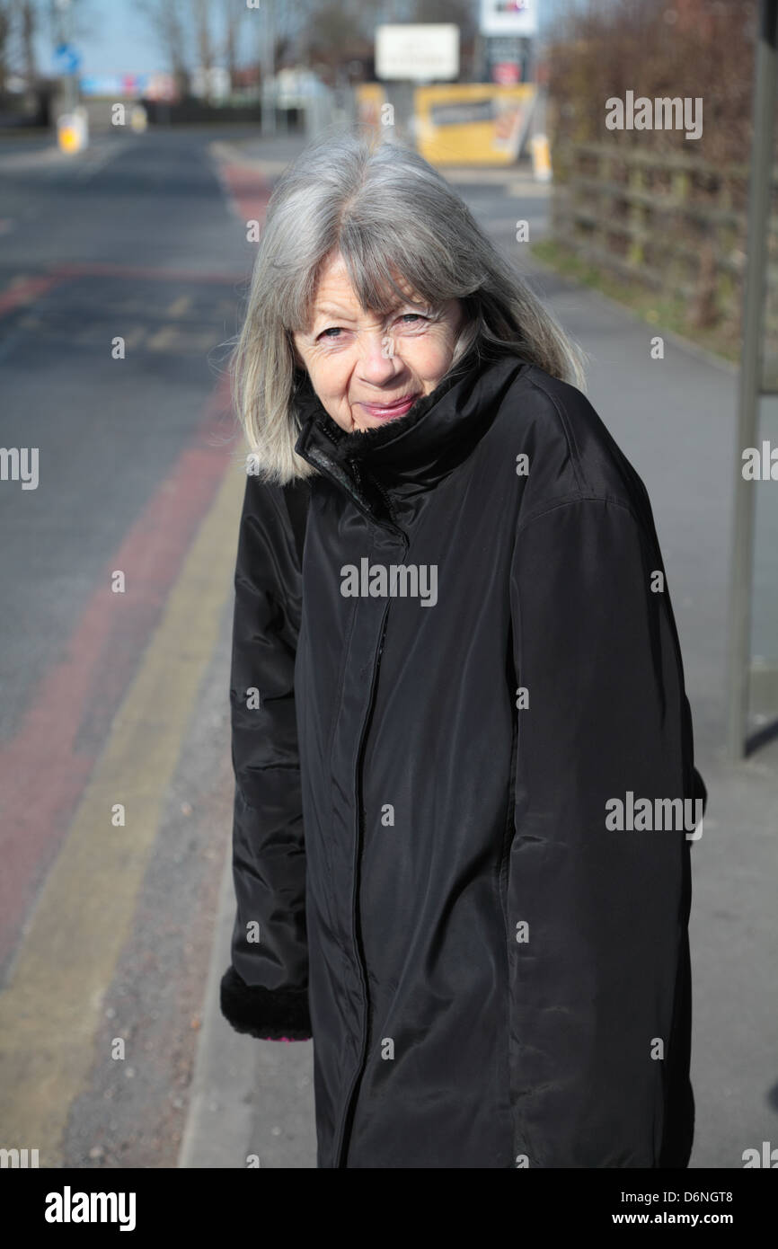 Woman standing at bus stop Stock Photo - Alamy